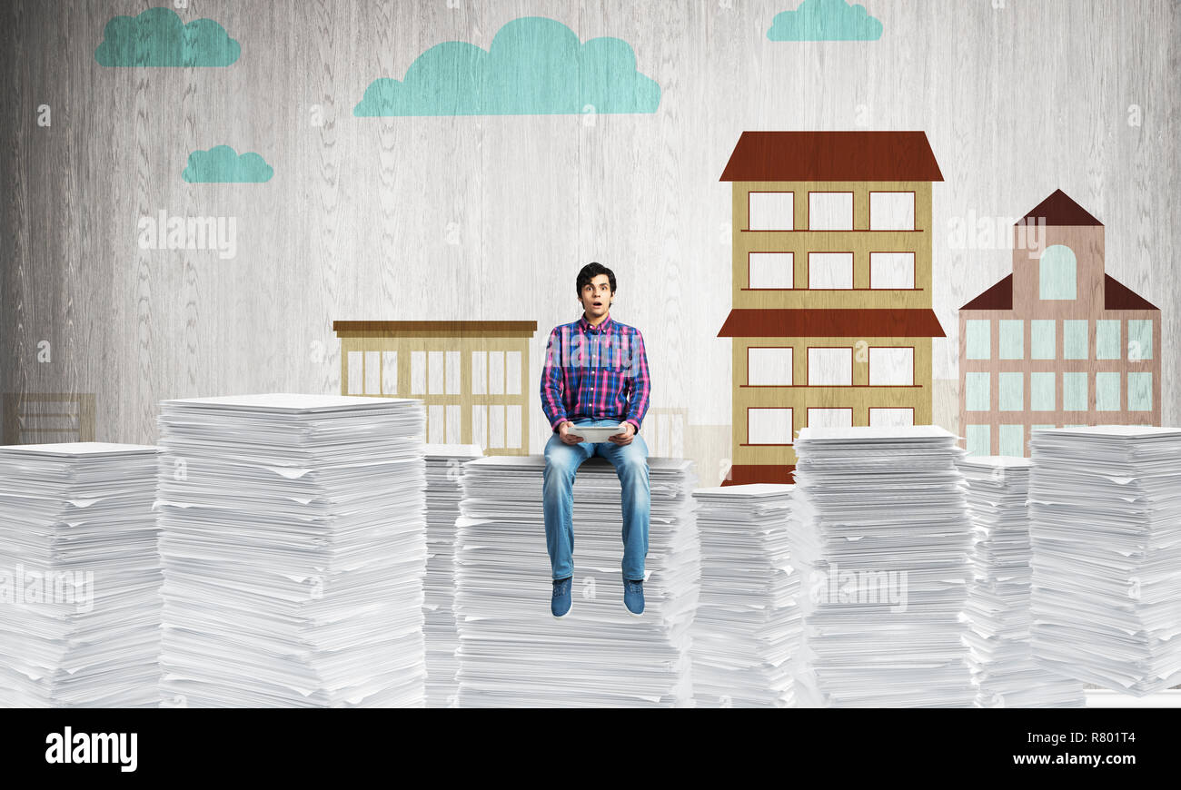 Young man sitting on pile of paper documents Stock Photo - Alamy
