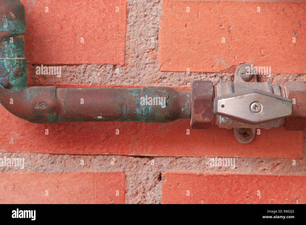 Gas pipes and valve in the open position against a red brick wall Stock ...