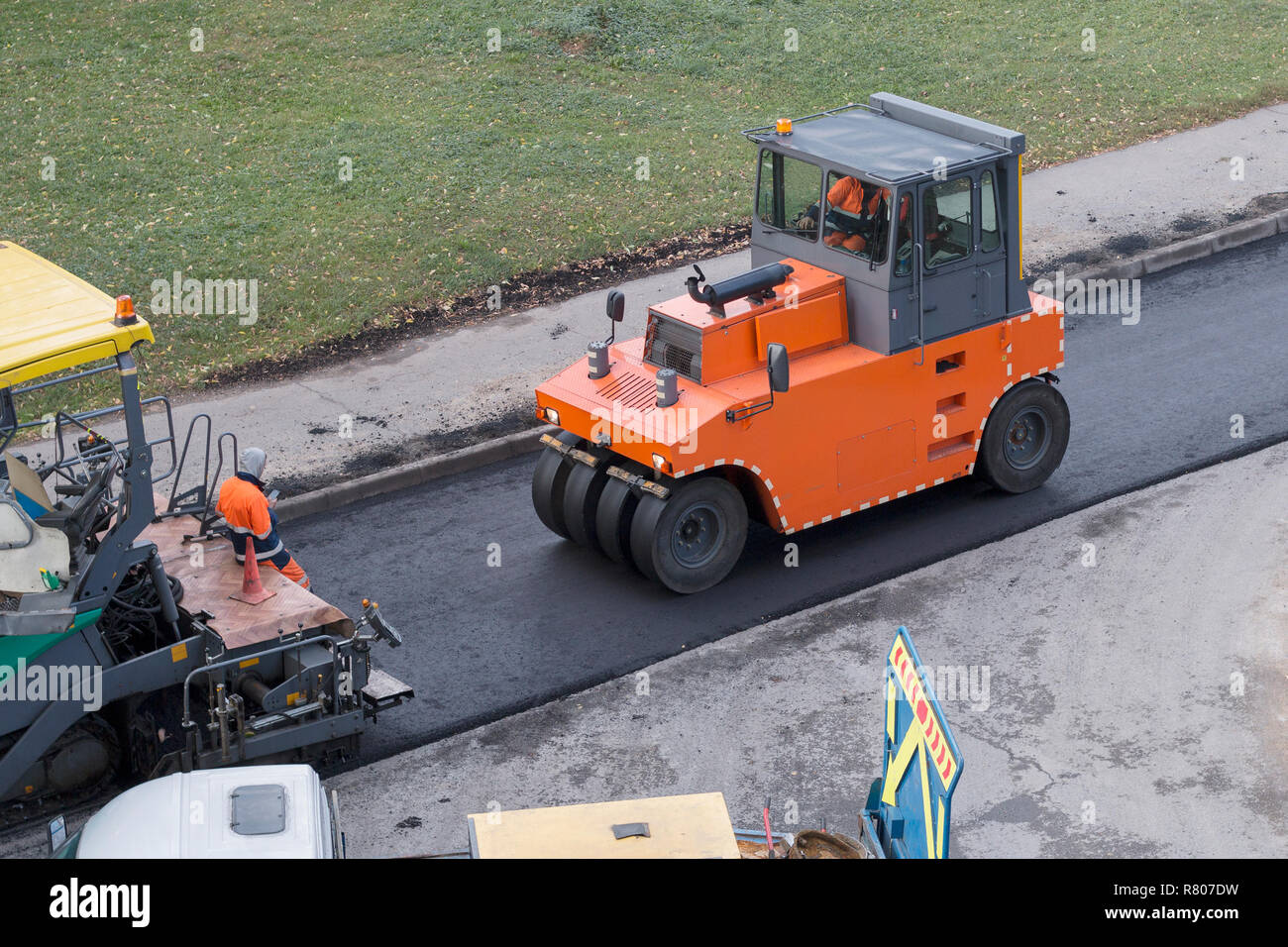 Road renewal process. Roller compactor machine presses new asphalt ...