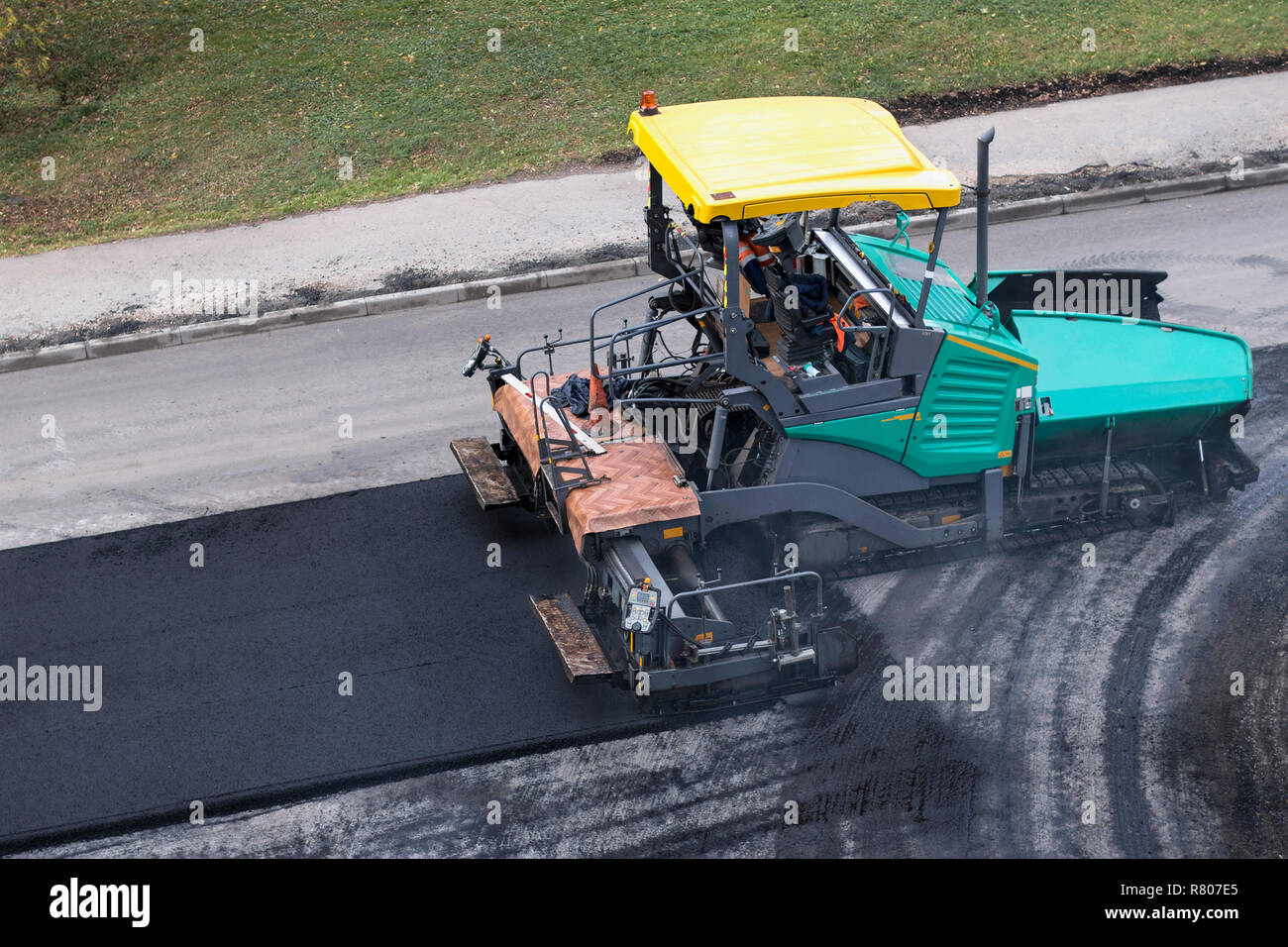 Asphalt paver machine or paver finisher places a layer of fresh hot ...