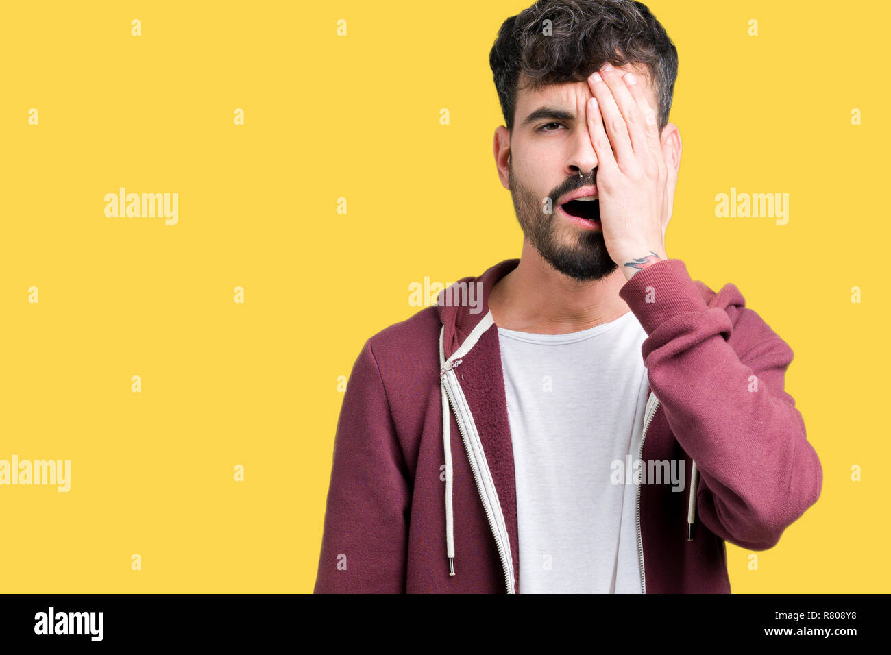 Young handsome man over isolated background Yawning tired covering half ...