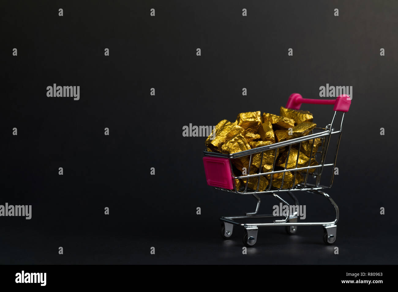 A pile of gold nuggets or gold ore in shopping cart or supermarket ...