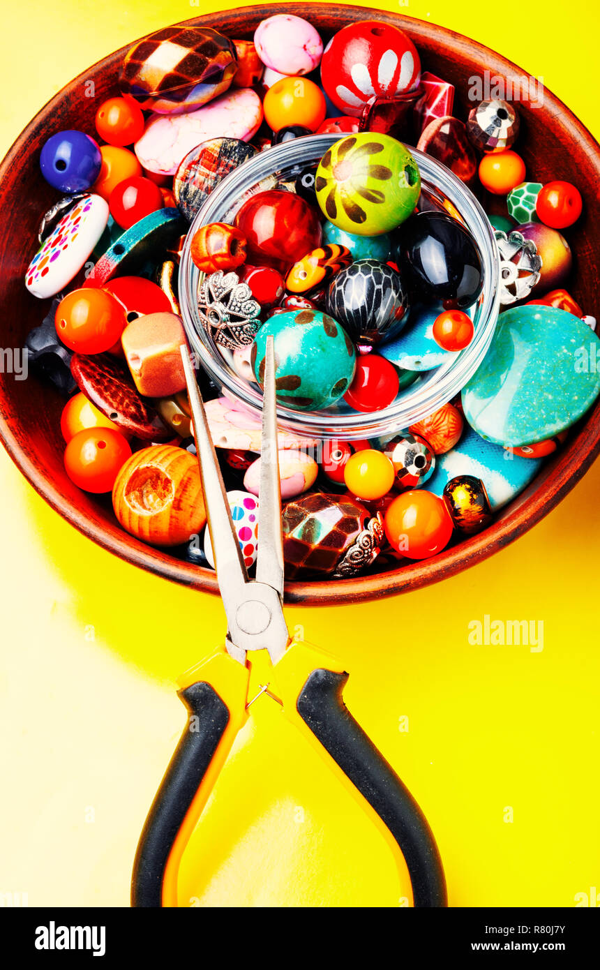 Jewelry making and beading process.Colored beads on yellow background ...