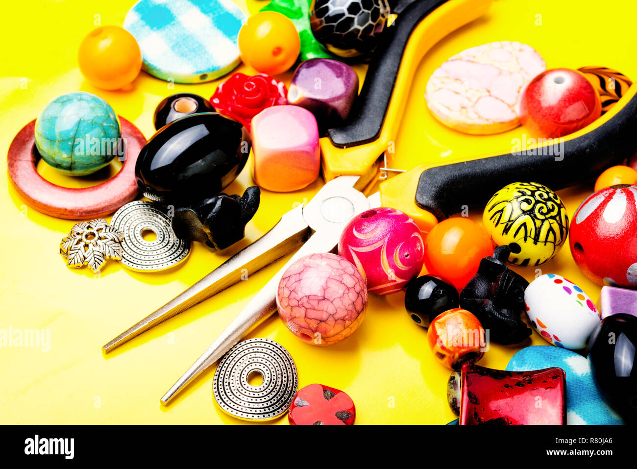 Jewelry making and beading process.Colored beads on yellow background ...