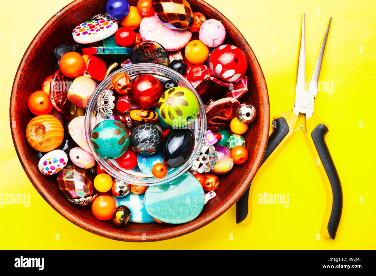 Jewelry making and beading process.Colored beads on yellow background ...