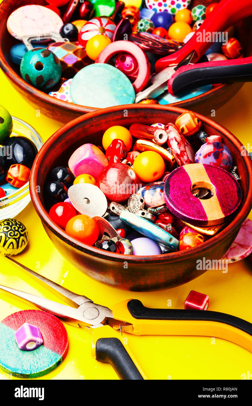 Jewelry making and beading process.Colored beads on yellow background ...