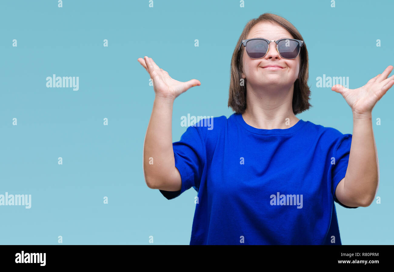 Young adult woman with down syndrome wearing sunglasses over isolated ...