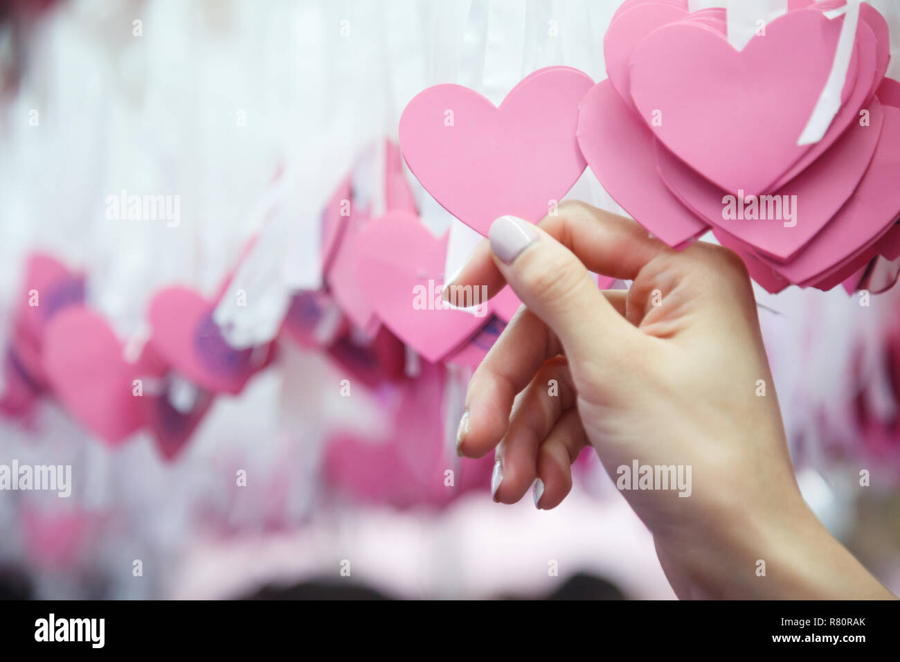 Woman Hand pick pink heart shape Lucky Draw attached to white ribbon on ...