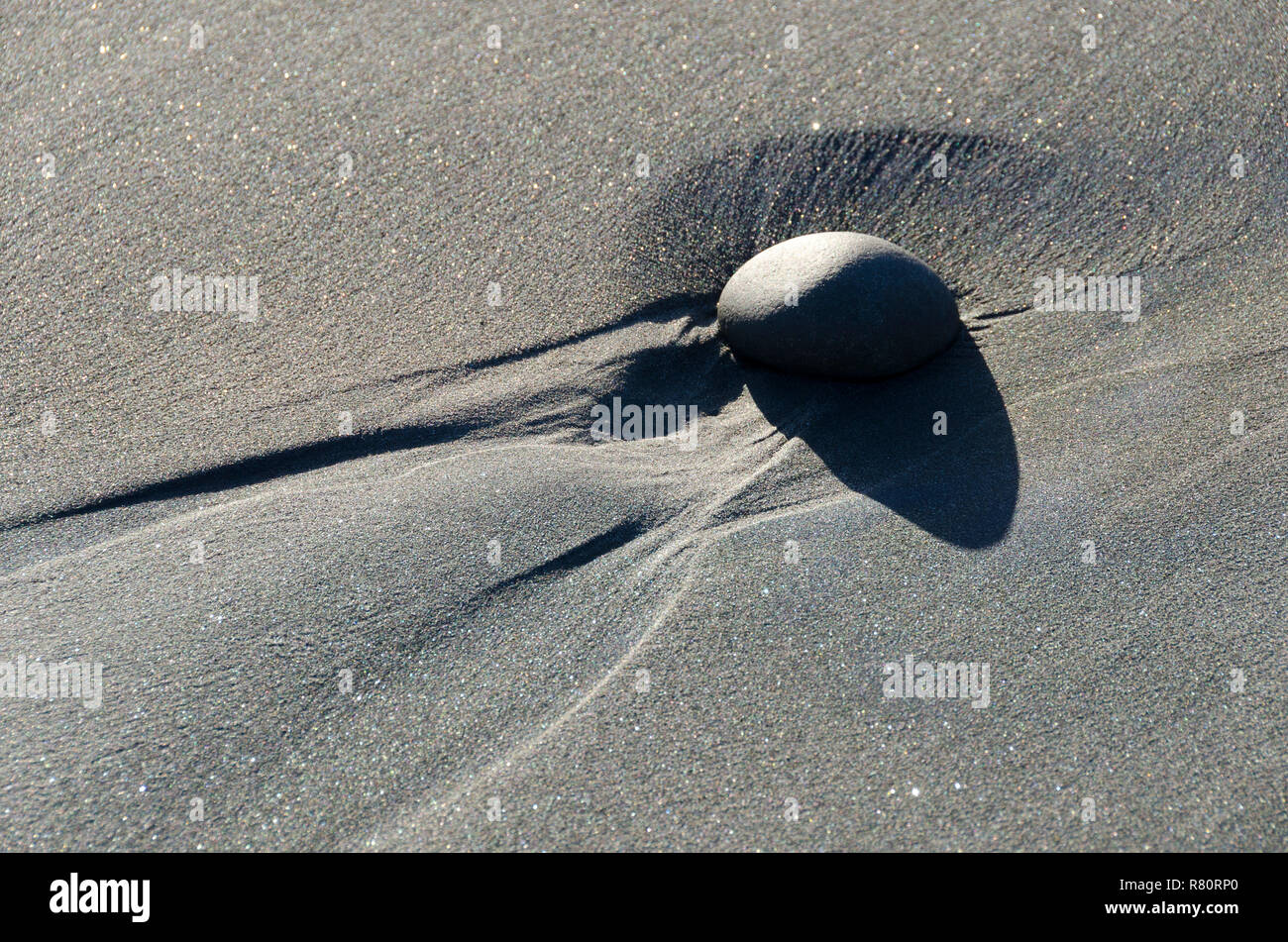 Stone on black sand beach, Onaero, Taranaki, North Island, New Zealand ...
