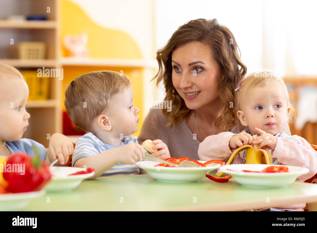 teacher and three preschoolers kids having break for fruits and ...