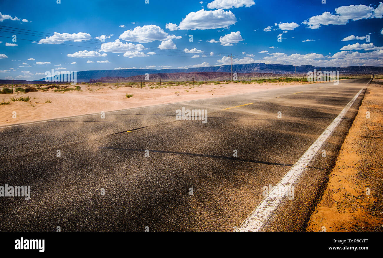 black asphalt highway with wind gust blowing red sand across inthe ...