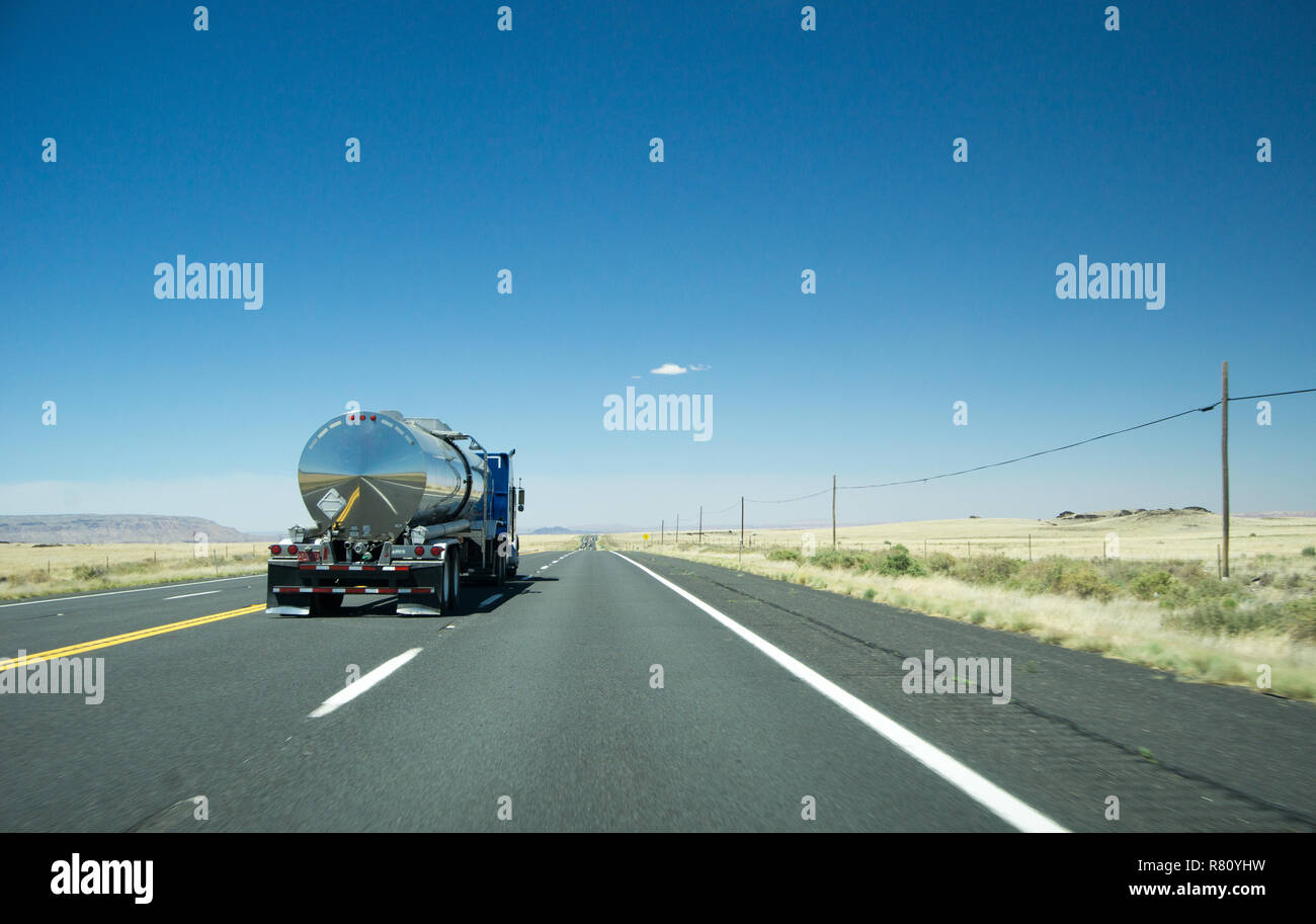 truck with a silver tank trailer passing a passenger car on a highway ...