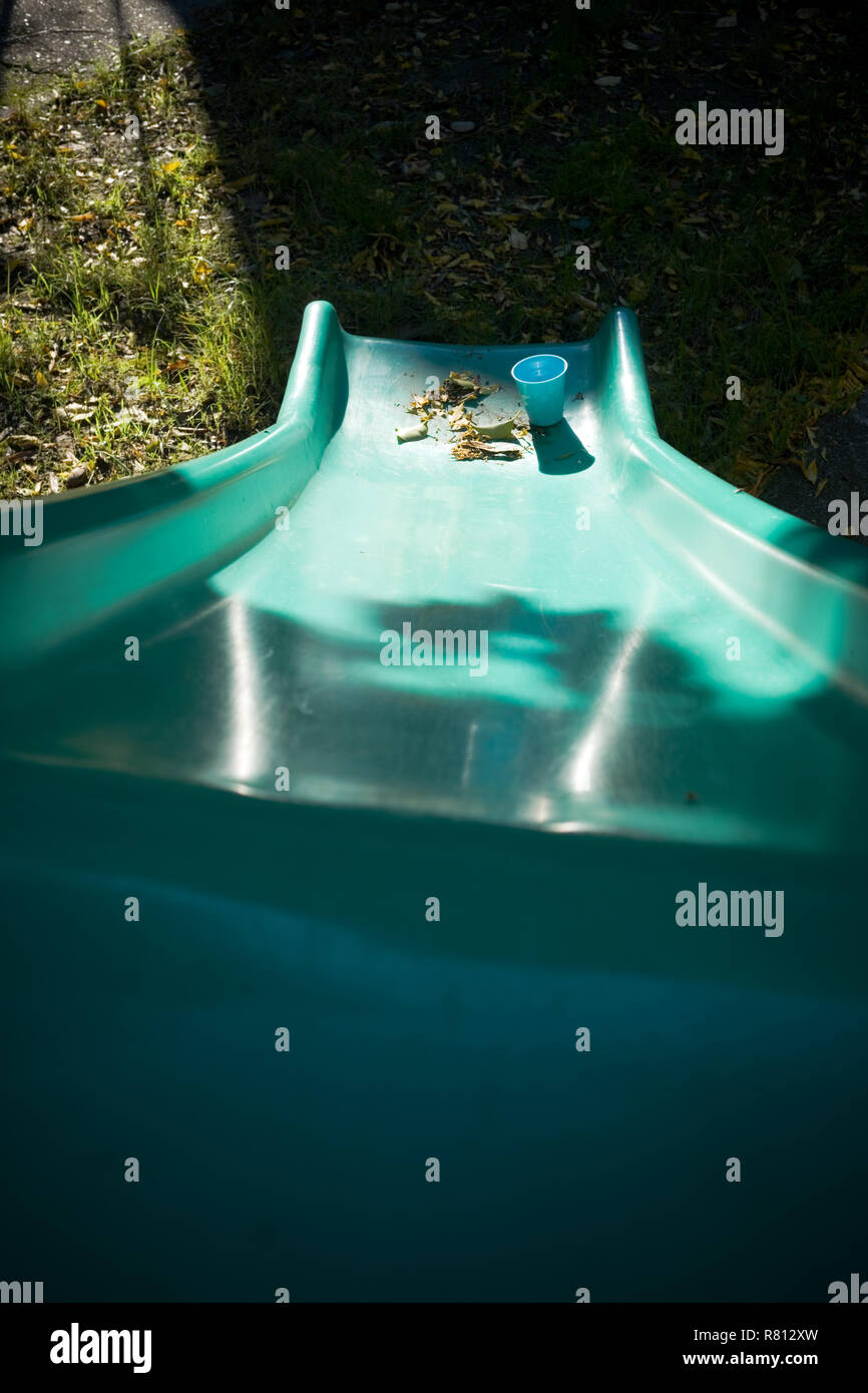 nostalgic shady shot in a garden looking down a plastic kid's slide ...