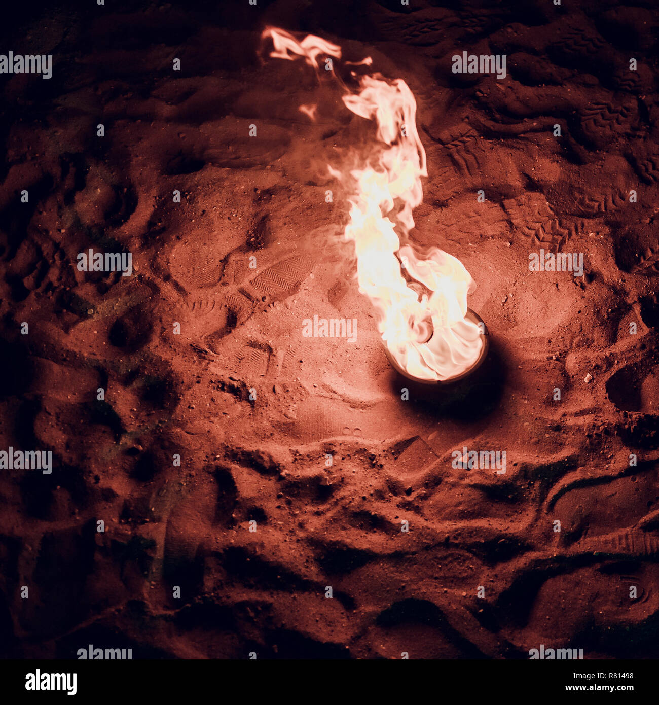 Fire in the top of a sand pyramid on the beach with incoming tide ...