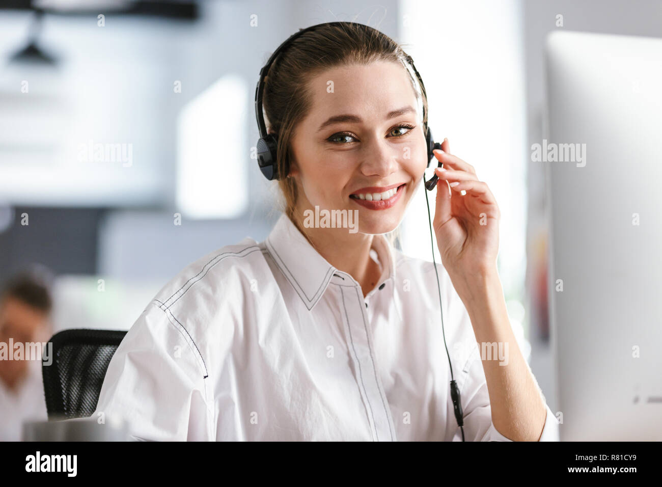 Happy young woman wearing microphone headset dressed in shirt sitting ...
