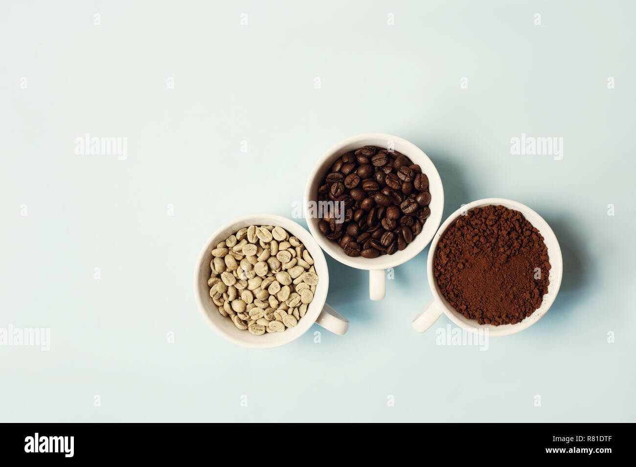 Different types of coffee - ground, grain and unroasted on blue pastel ...