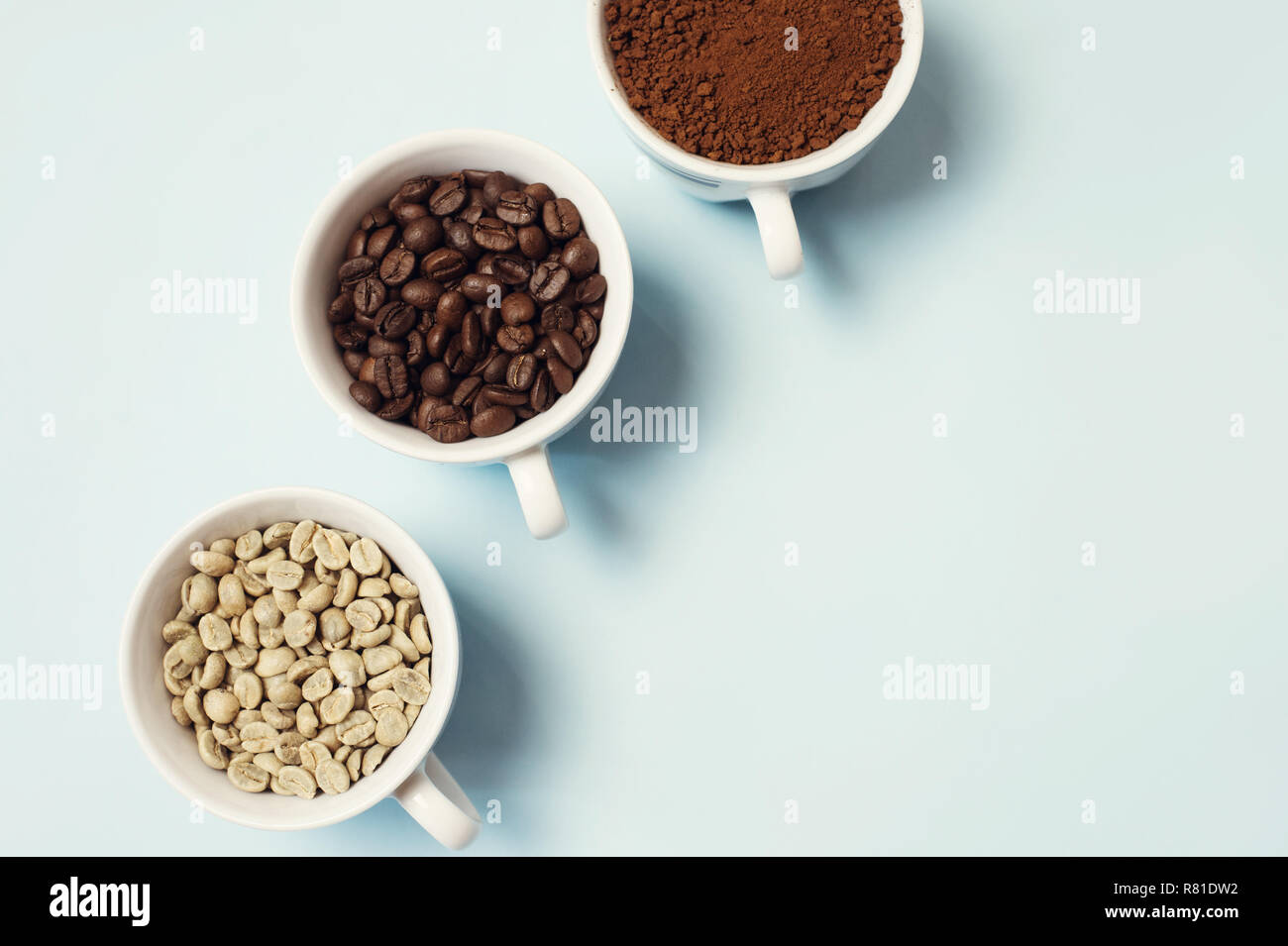 Different types of coffee - ground, grain and unroasted on blue pastel ...