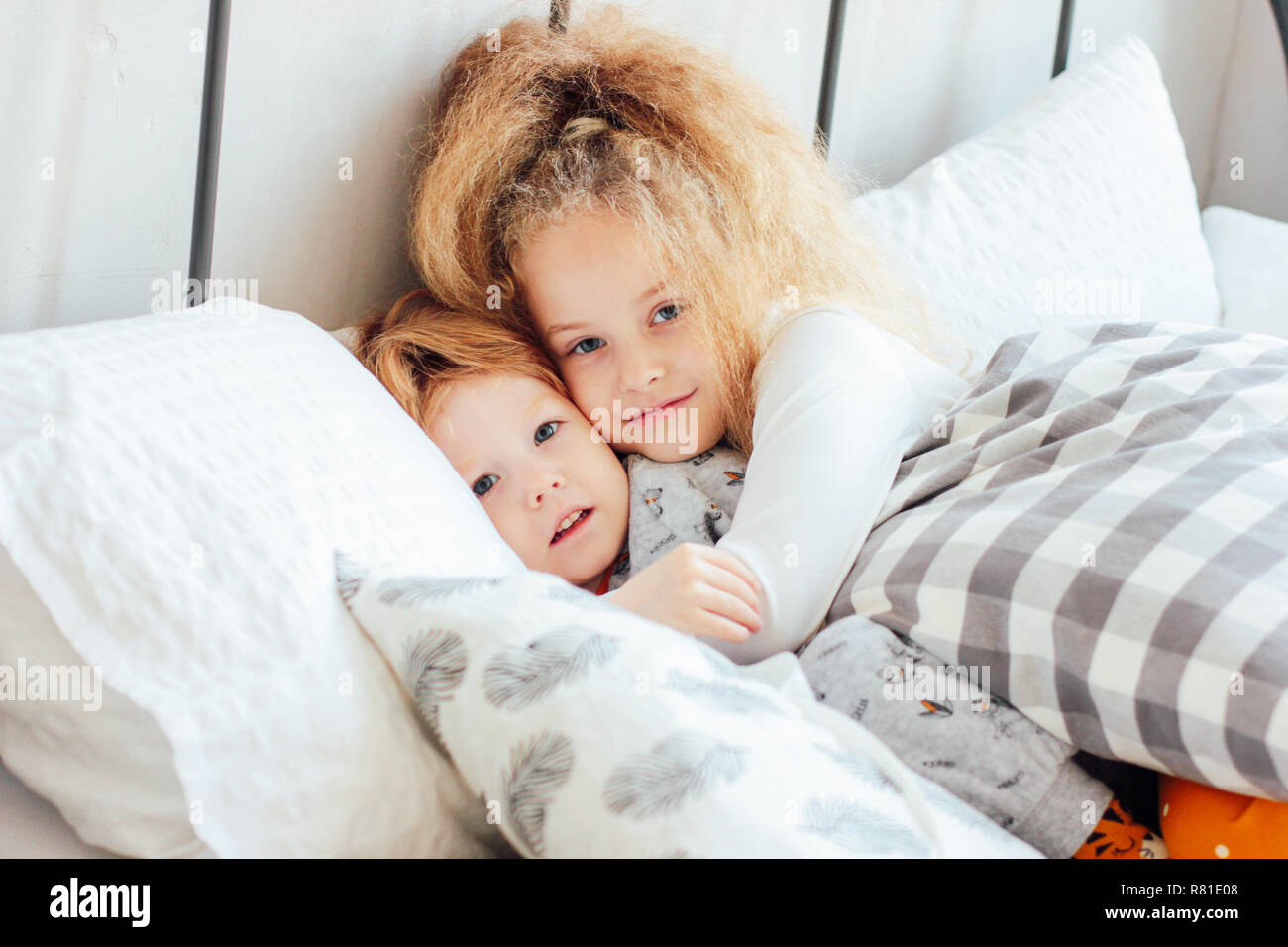 Little cute brother and sister in pajamas lie in bed, cozy morni Stock ...