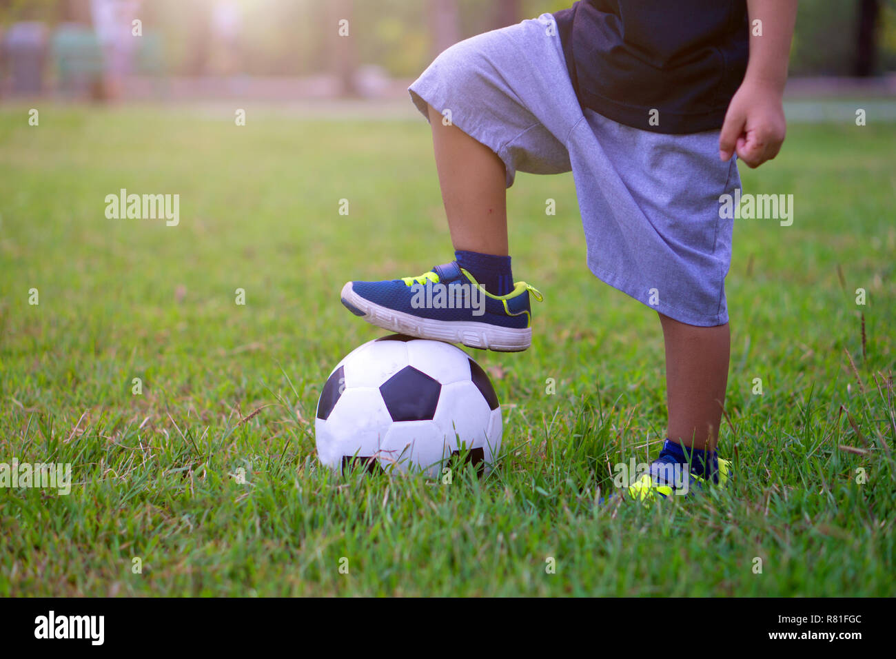 Asian kid playing soccer or football in the park. Step on the ball ...