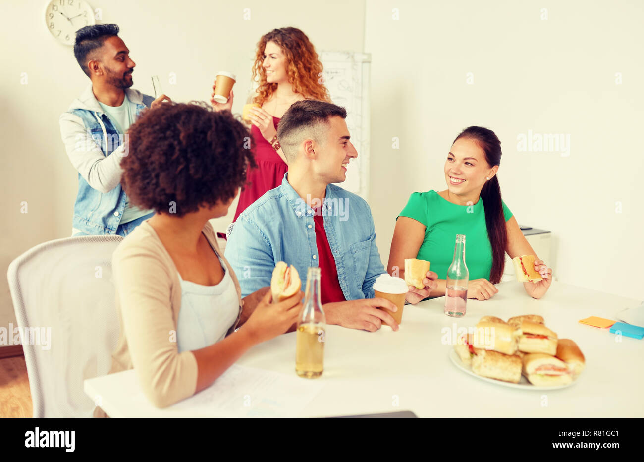 happy friends or team eating at office Stock Photo - Alamy