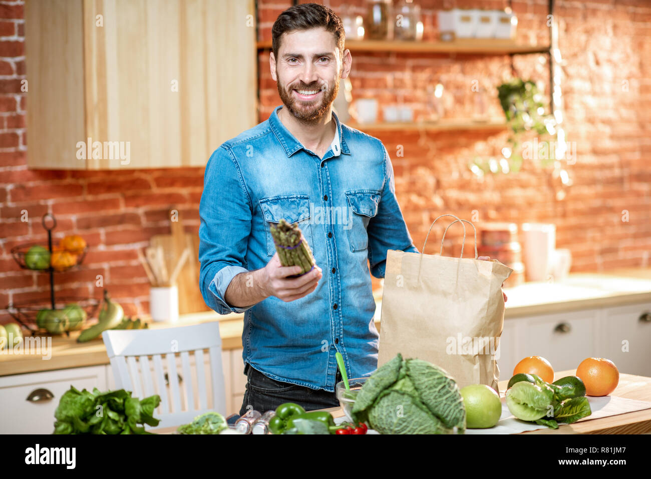 Handsome man in blue shirt unpacking healthy food from the shopping bag ...
