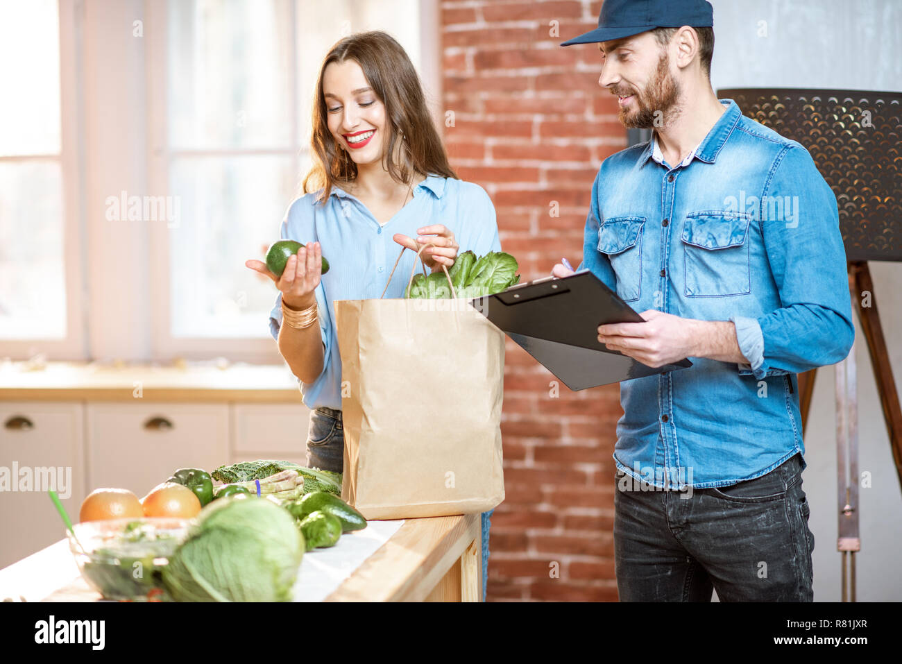 Woman client cheking products standing with delivery worker on the ...