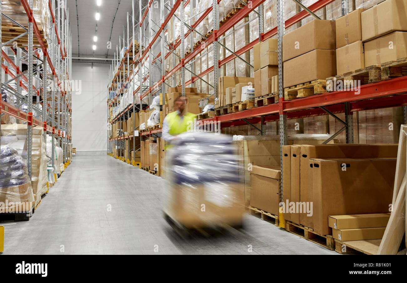 worker carrying loader with goods at warehouse Stock Photo - Alamy