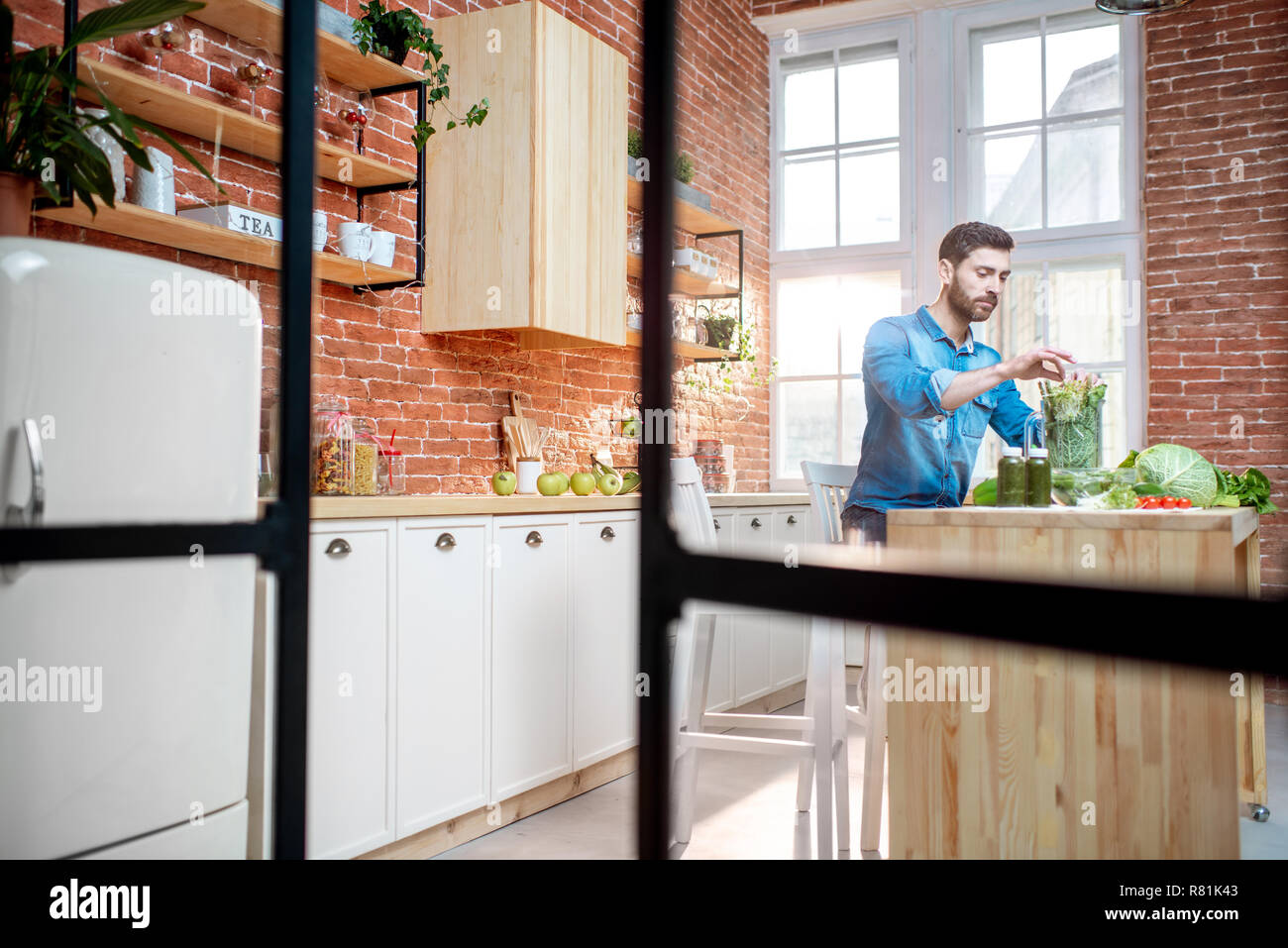 Vegetarian man with raw products on the kitchen, wide interior view on ...