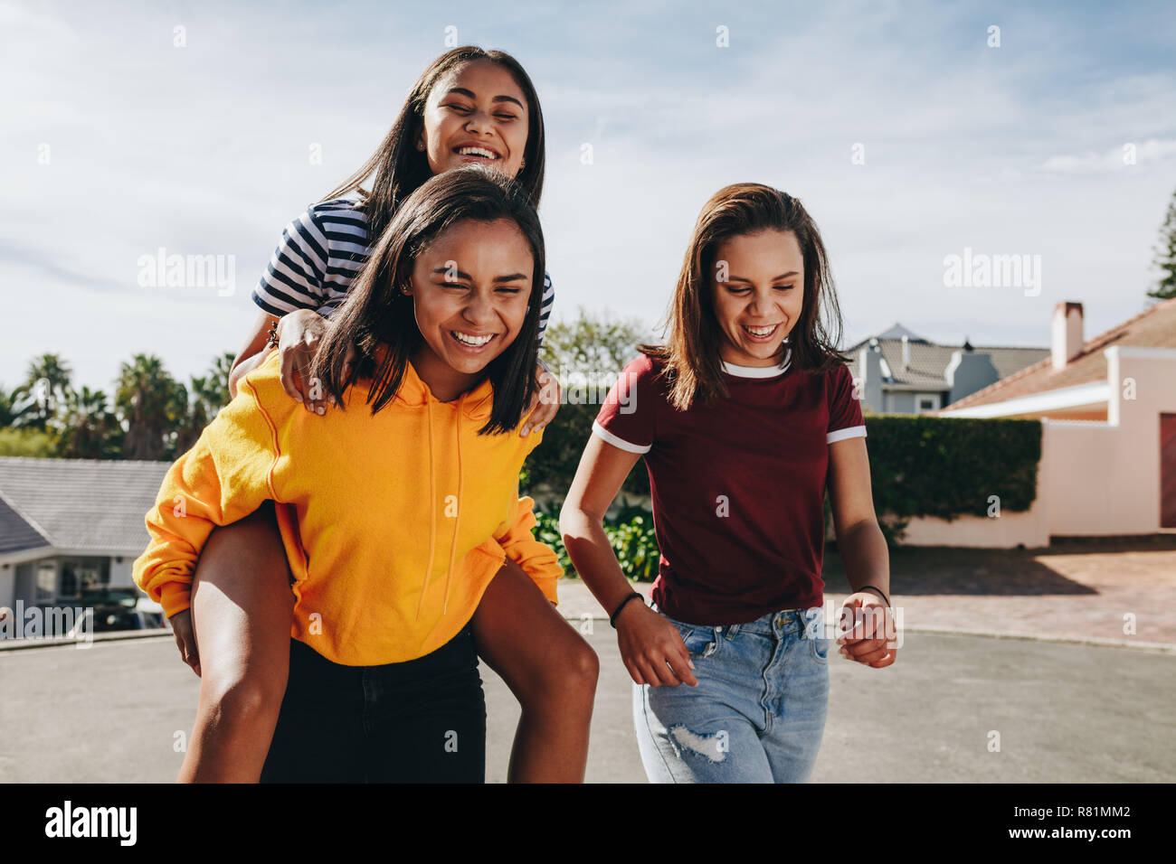 Girl carrying her friend on her back while walking in the street ...