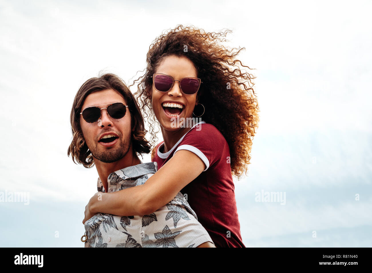 Laughing woman riding on boyfriends back outdoors. Couple enjoying ...