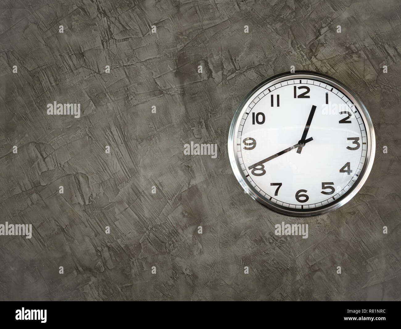 White steel round shape clock on grey concrete wall with copy space ...