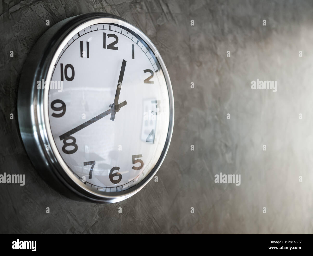 White steel round shape clock on grey concrete wall with copy space ...