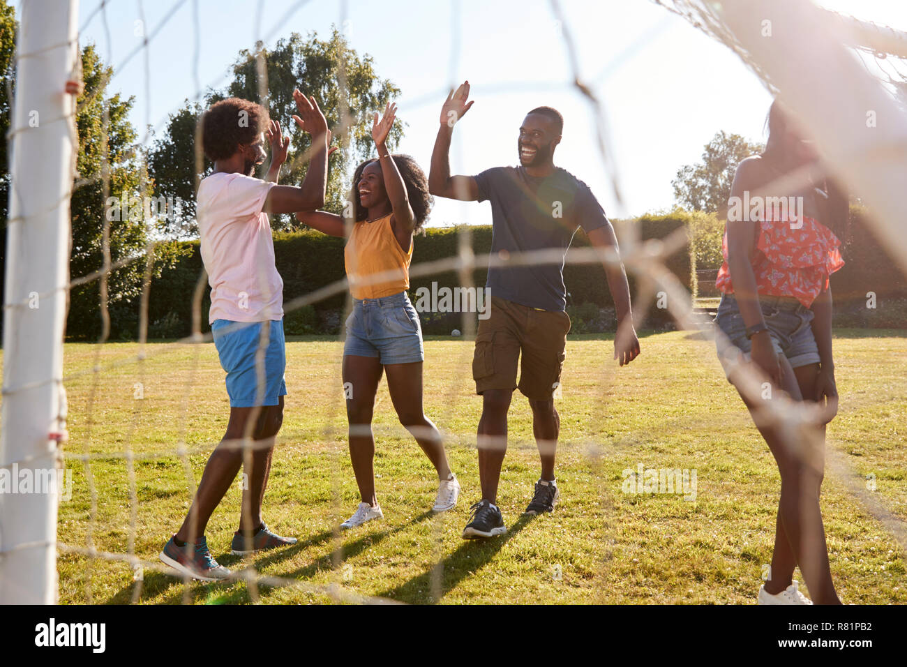 Black adult friends high five during a fun game of football Stock Photo ...