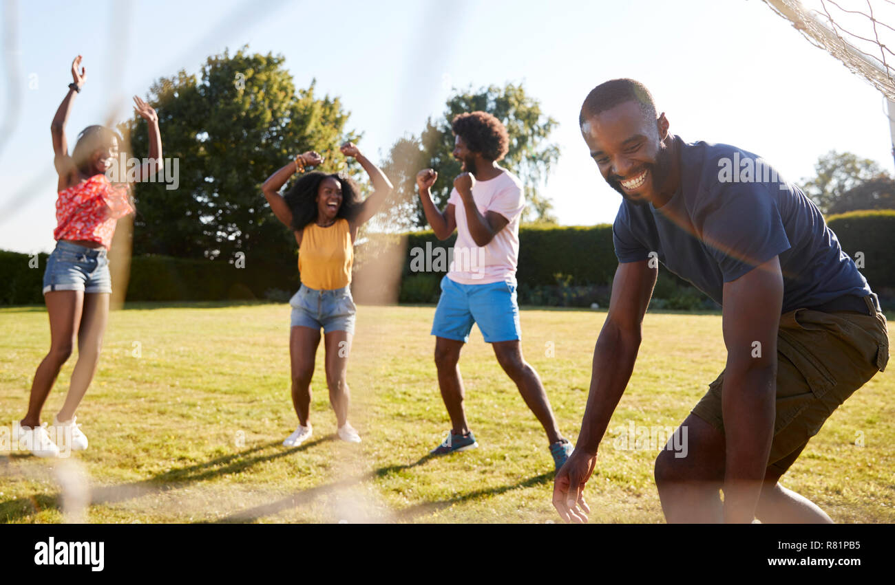 Adult friends celebrate scoring goal during fun soccer game Stock Photo ...