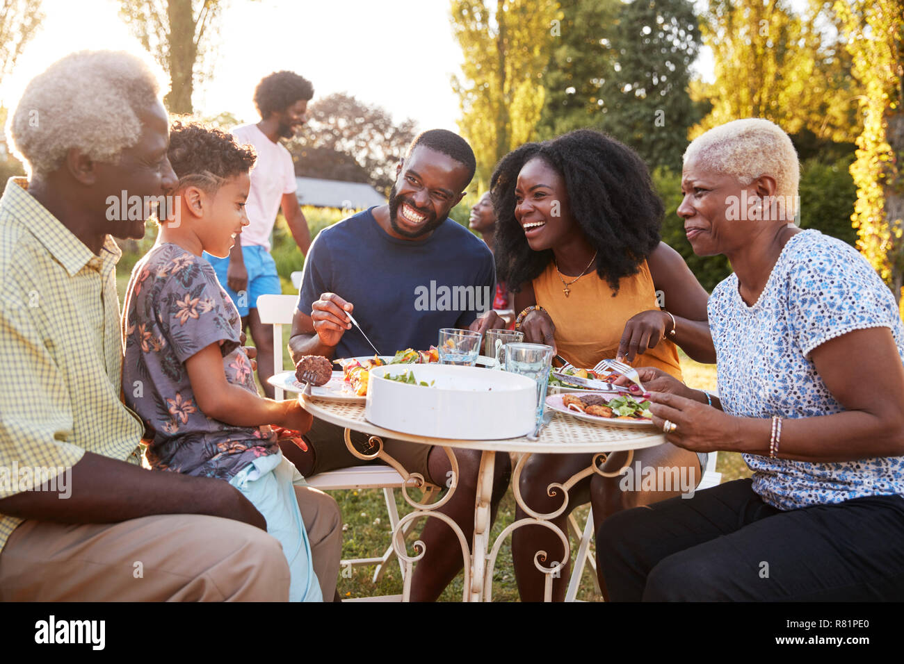 Black multi generation family eating at a table in garden Stock Photo ...