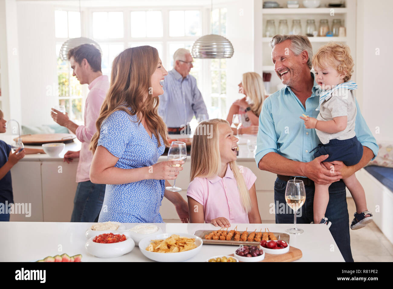 Multi-Generation Family And Friends Gathering In Kitchen For ...
