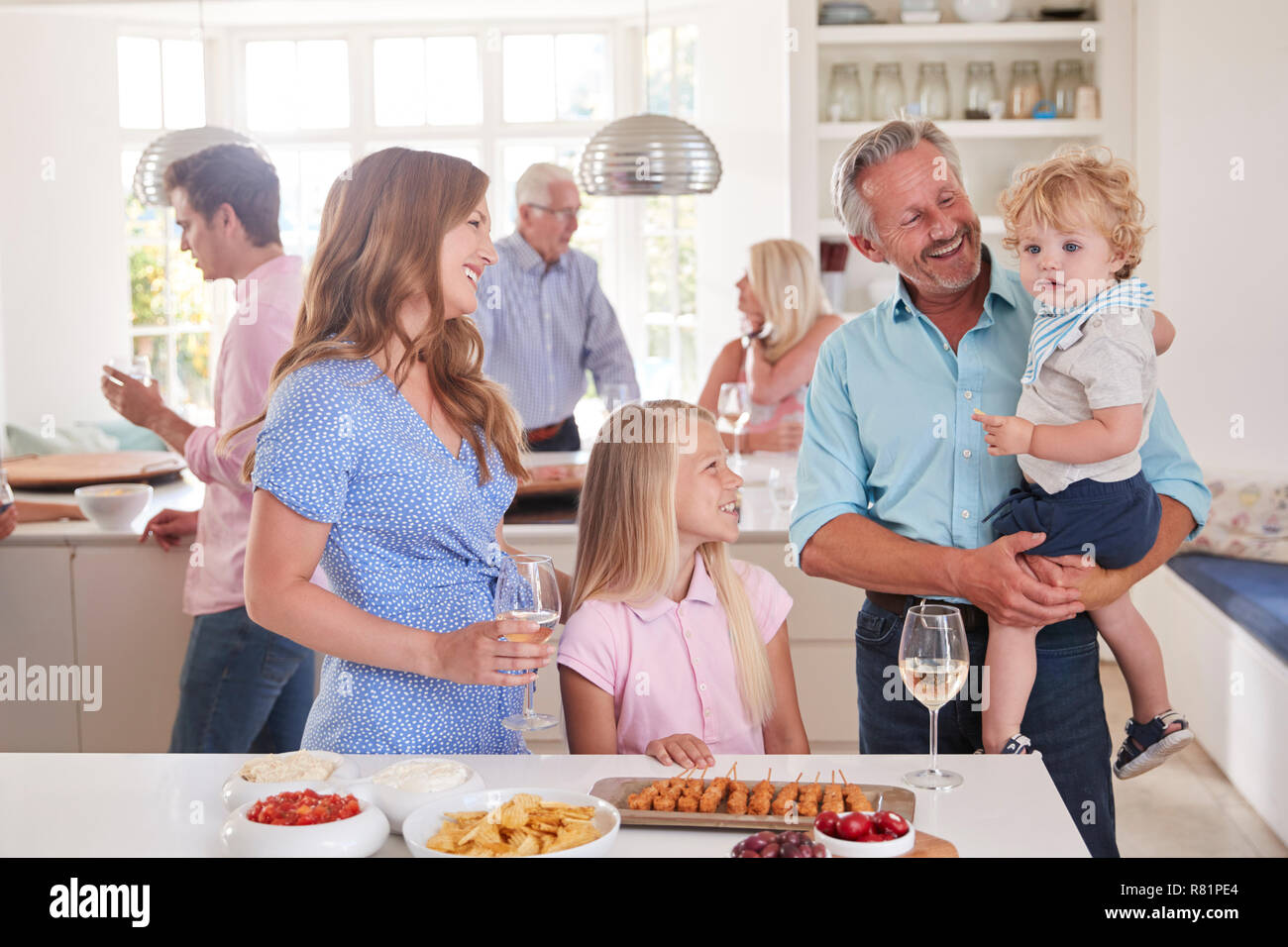 Multi-Generation Family And Friends Gathering In Kitchen For ...
