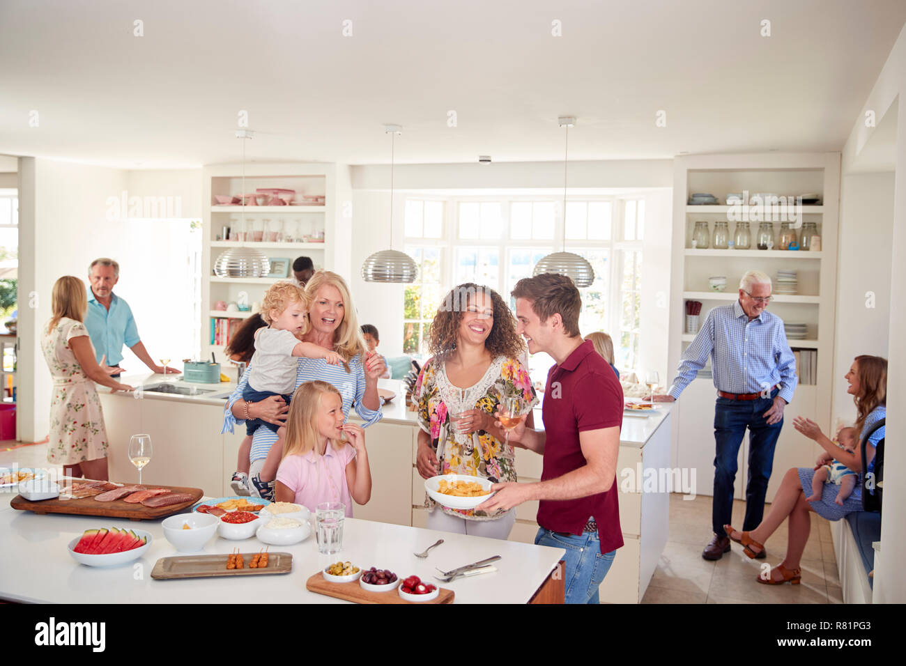 Multi-Generation Family And Friends Gathering In Kitchen For ...