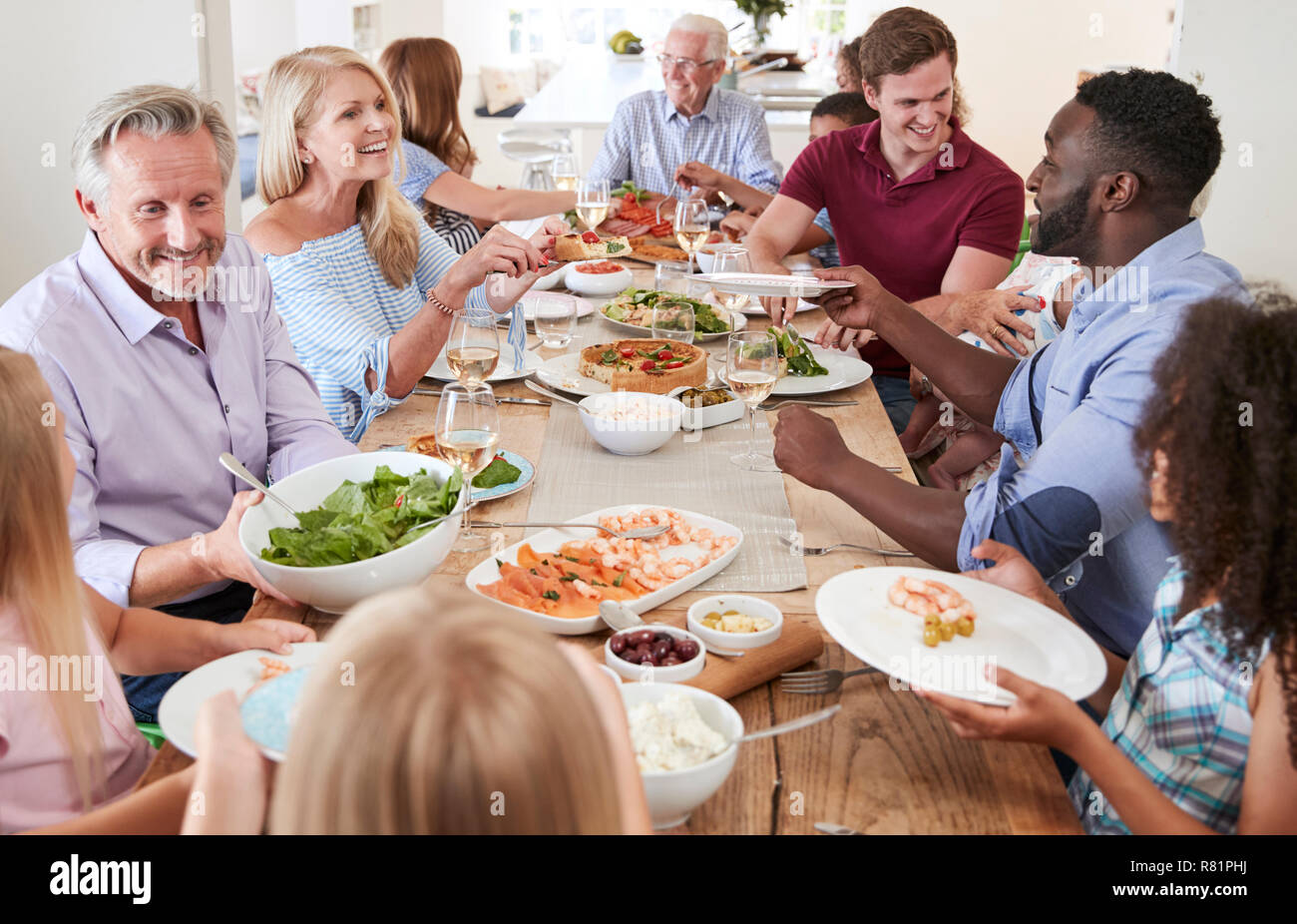 Group Of Multi-Generation Family And Friends Sitting Around Table And ...