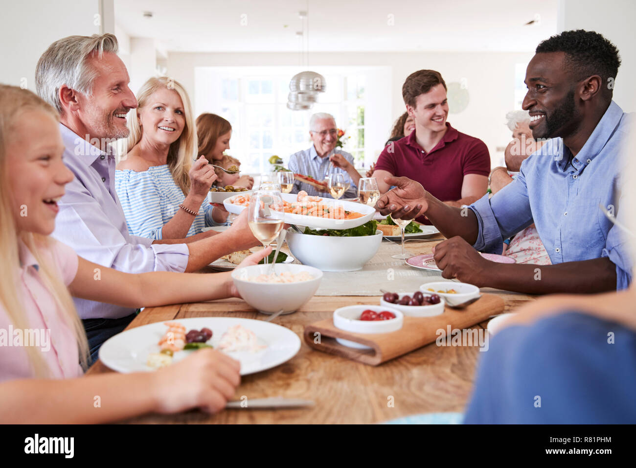 Group Of Multi-Generation Family And Friends Sitting Around Table And ...