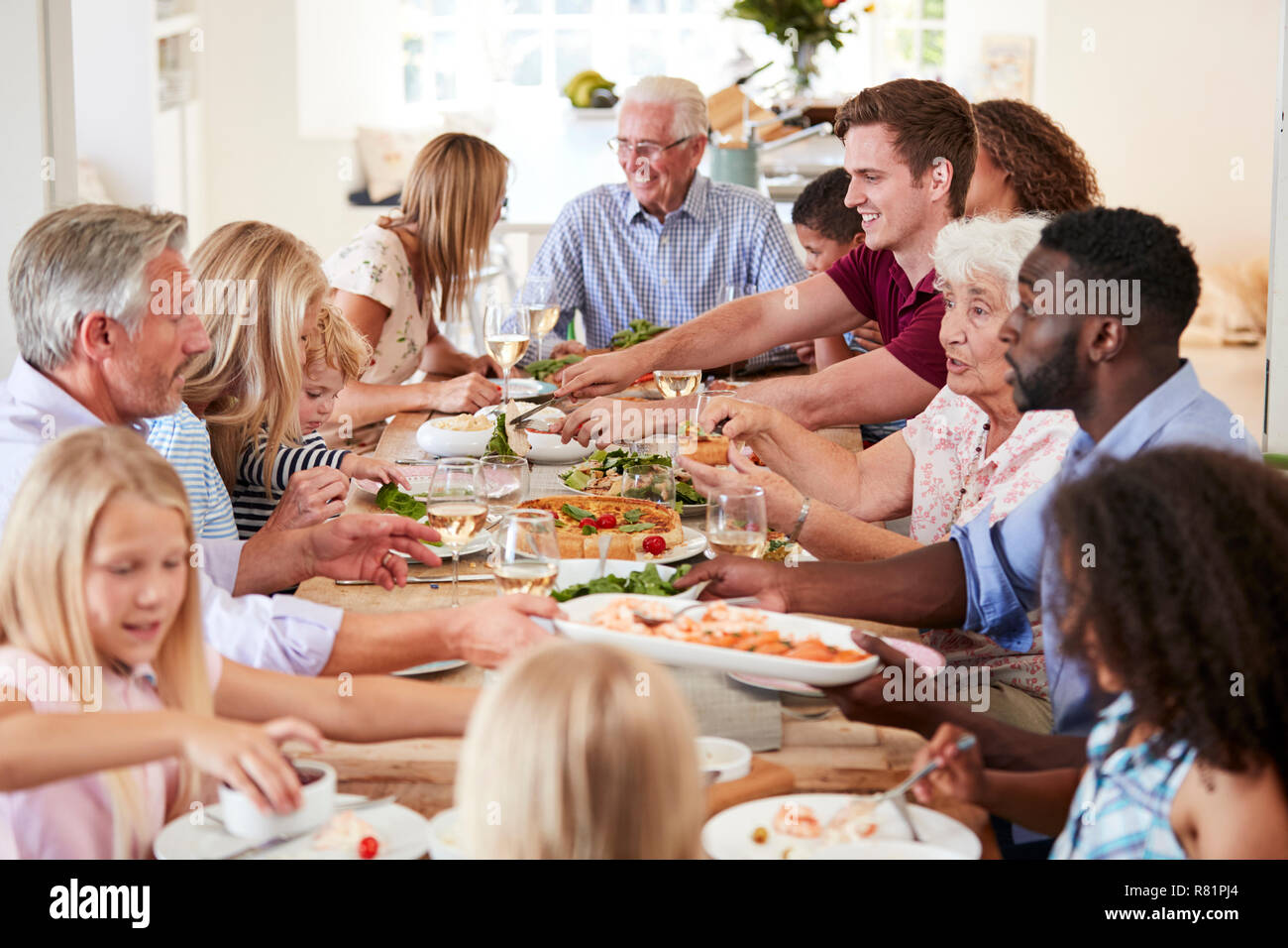 Group Of Multi-Generation Family And Friends Sitting Around Table And ...