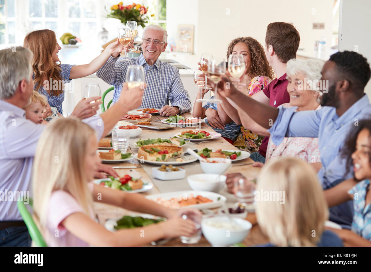 Group Of Multi-Generation Family And Friends Sitting Around Table And ...