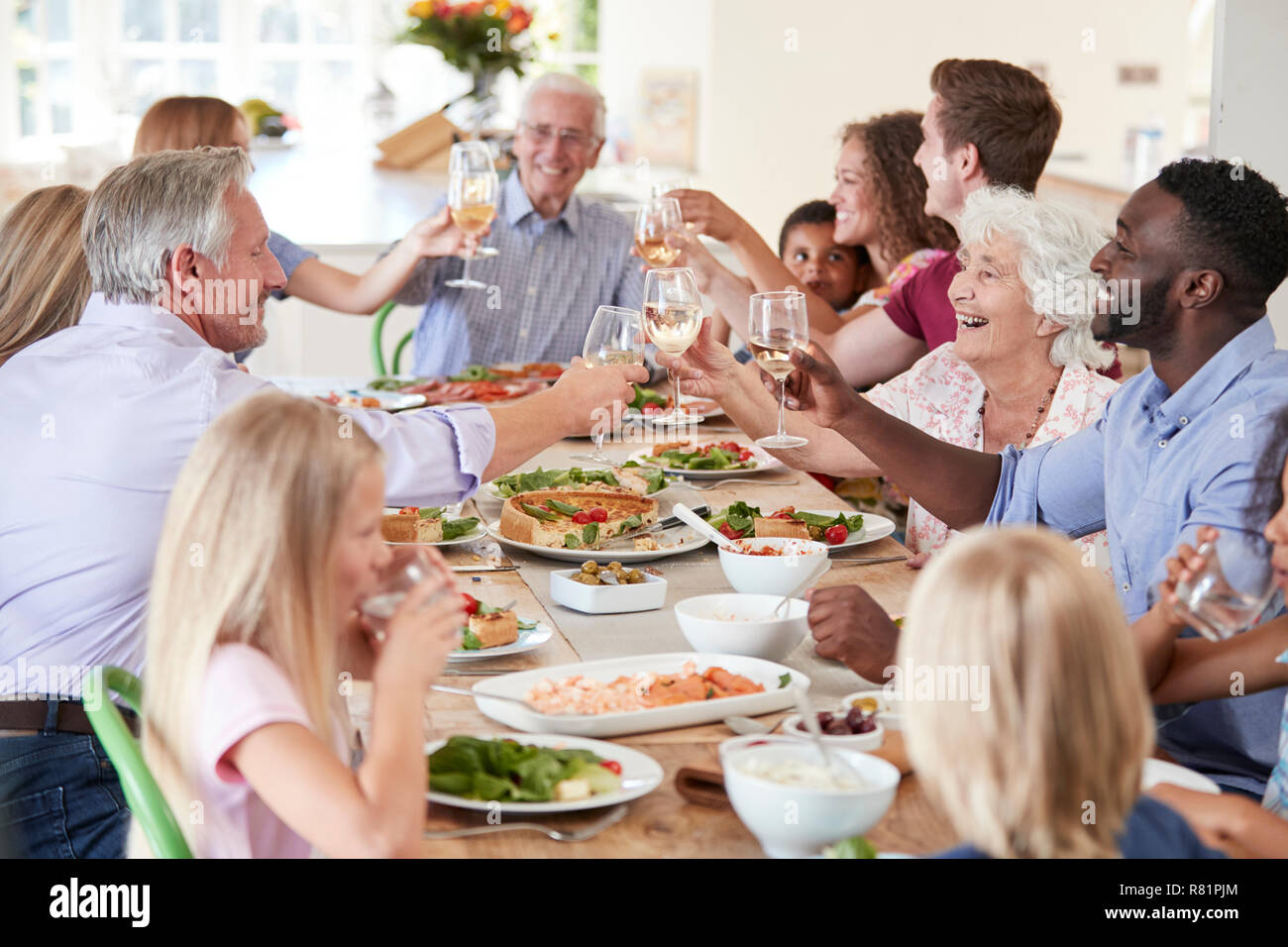 Group Of Multi-Generation Family And Friends Sitting Around Table And ...