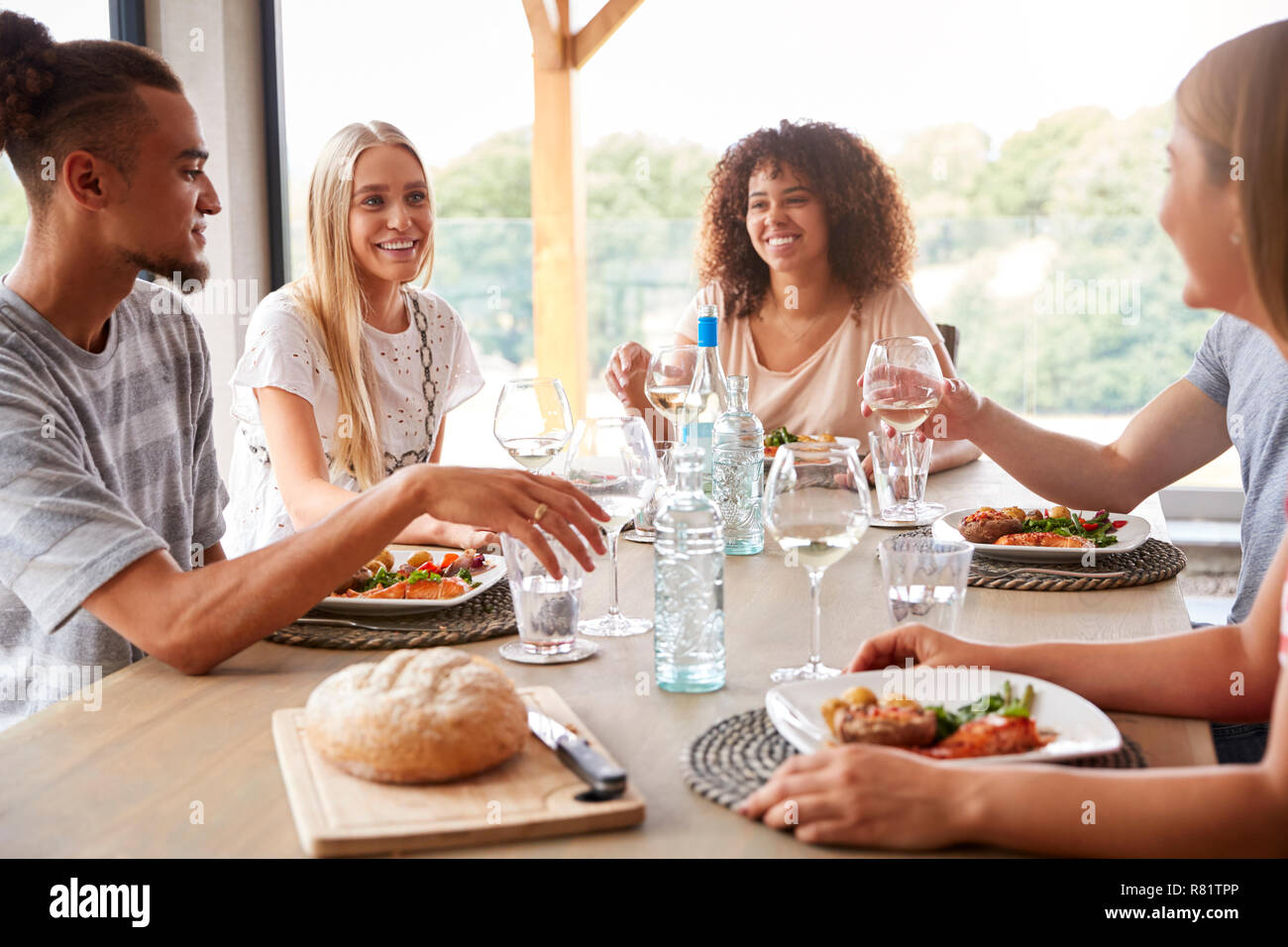 Multi ethnic group of five young adult friends eating, drinking ...