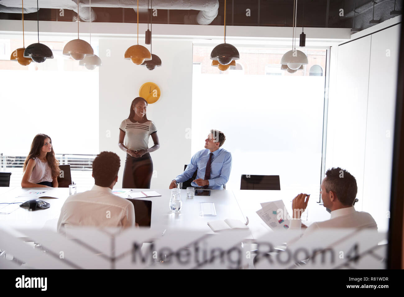 Businesswoman Giving Boardroom Presentation Viewed Through Meeting Room ...