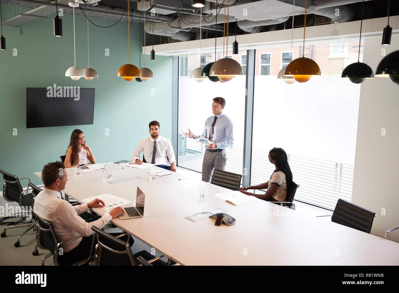 Businessman Giving Boardroom Presentation To Colleagues In Meeting Room ...