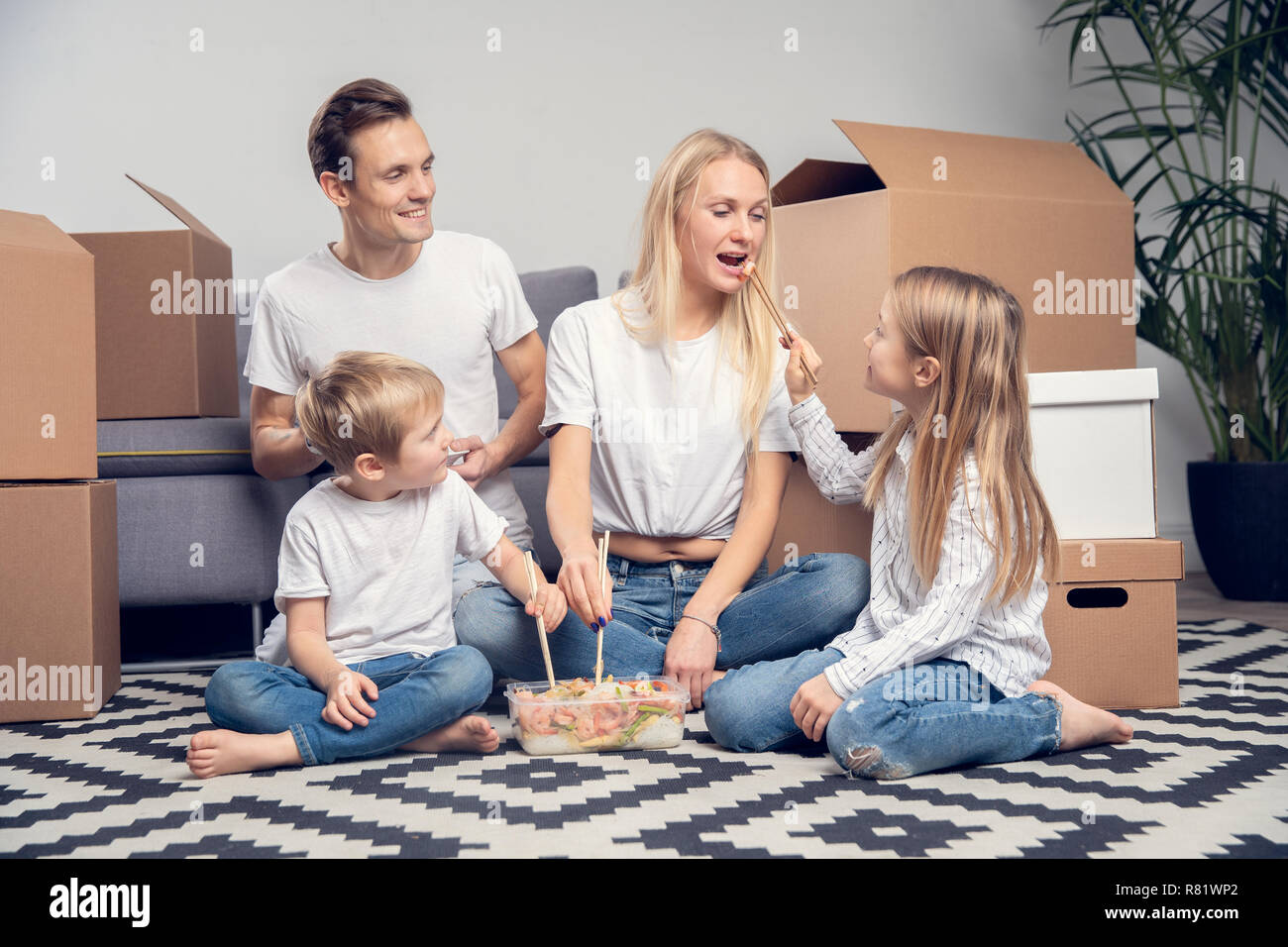 Photo of young couple with children eating rice with shrimps sitting on ...