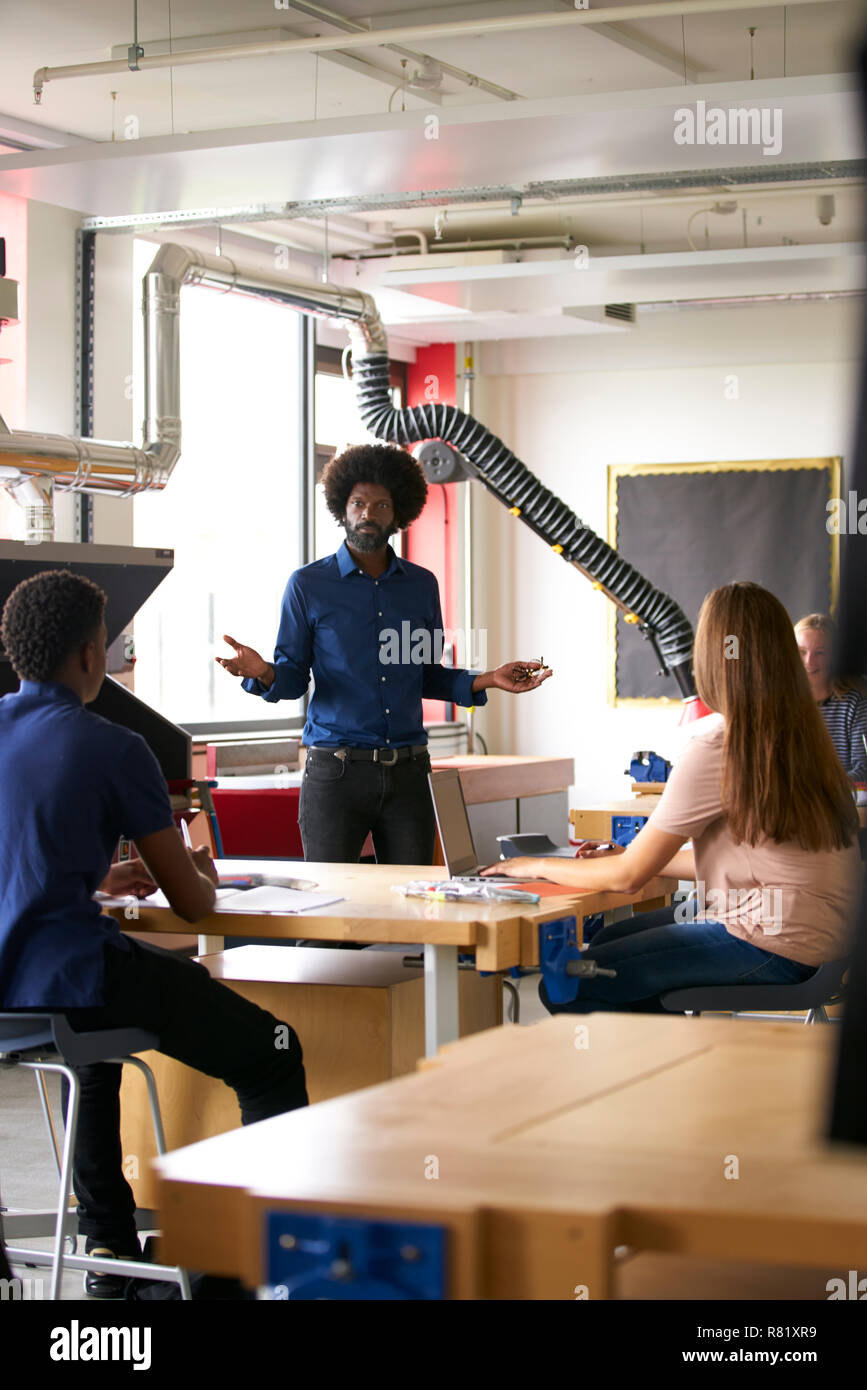 Class Of High School Students Sitting At Work Benches Listening To ...
