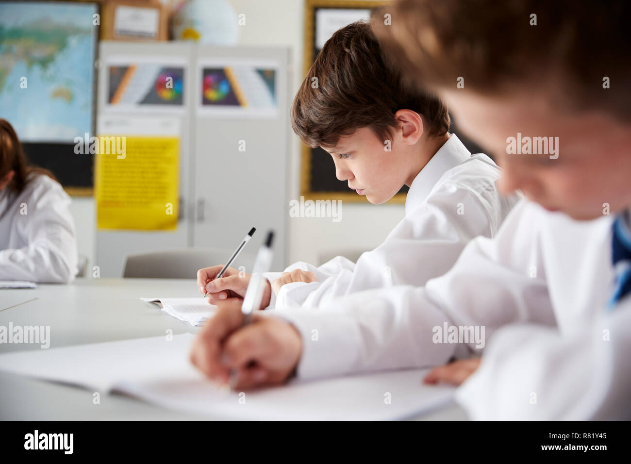 High School Students Wearing Uniform Sitting And Working Around Table ...