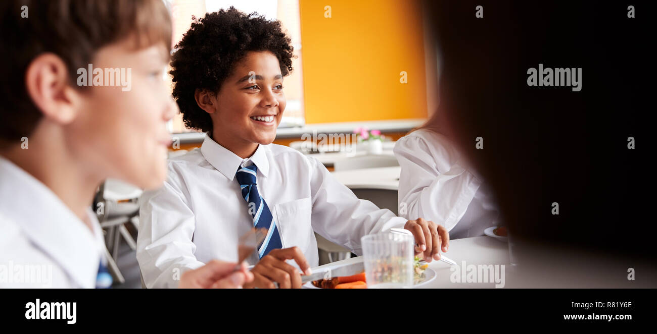 Group Of High School Students Wearing Uniform Sitting Around Table And ...